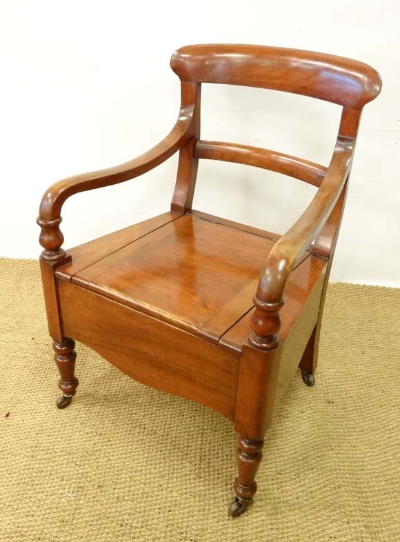A Victorian walnut commode with open arms and turned