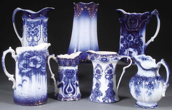 A GROUP OF SEVEN VICTORIAN FLOW BLUE PITCHERS.