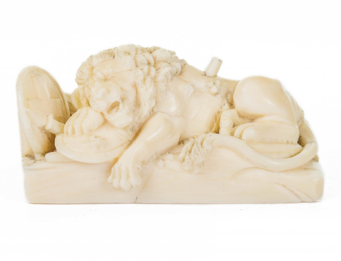 AN ANTIQUE CARVED IVORY LION STATUE