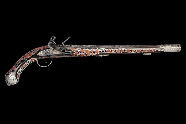 83: A silver and coral mounted flintlock pistol