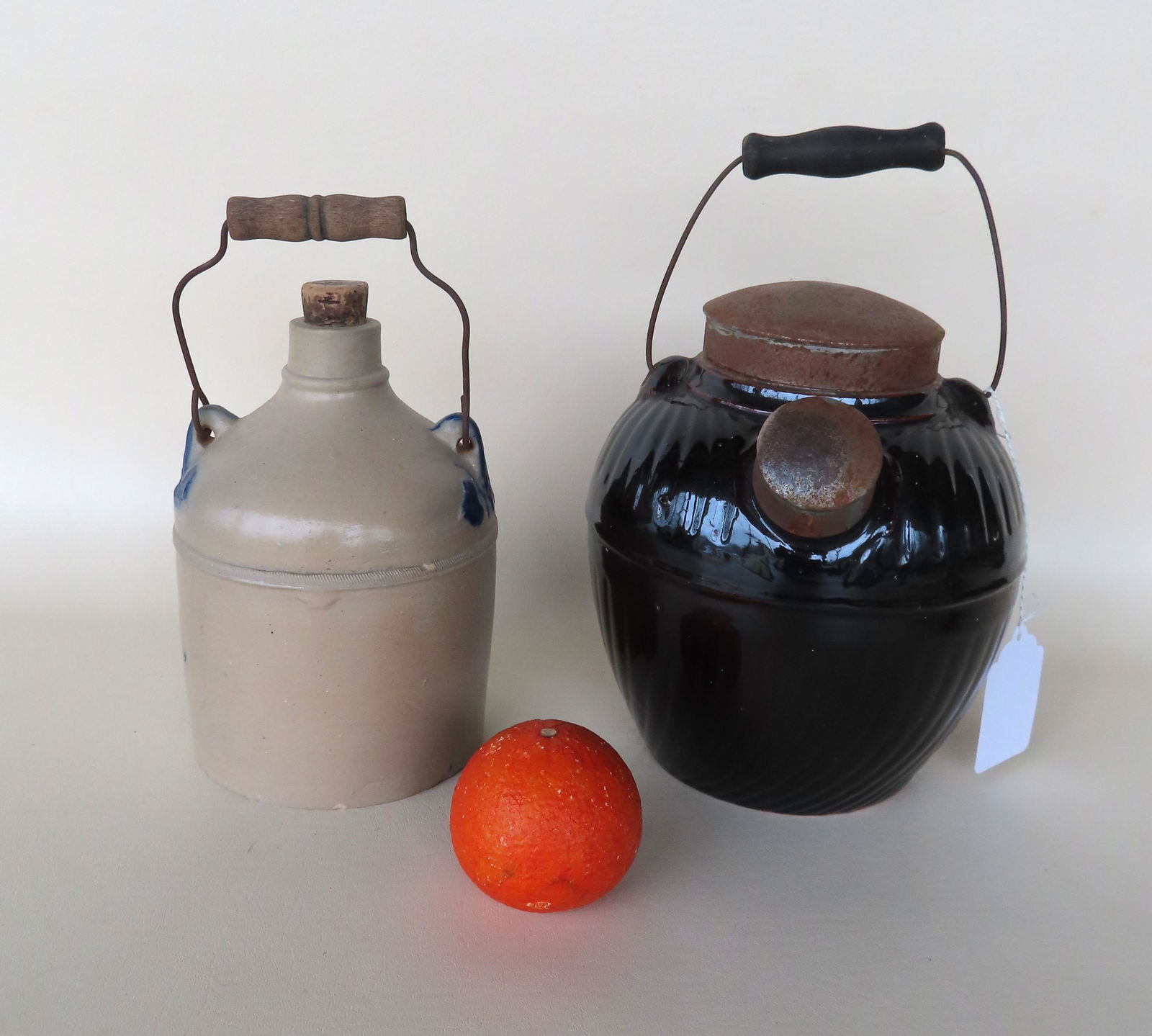 Two stoneware jugs. The first with a wire bail handle attached to ...