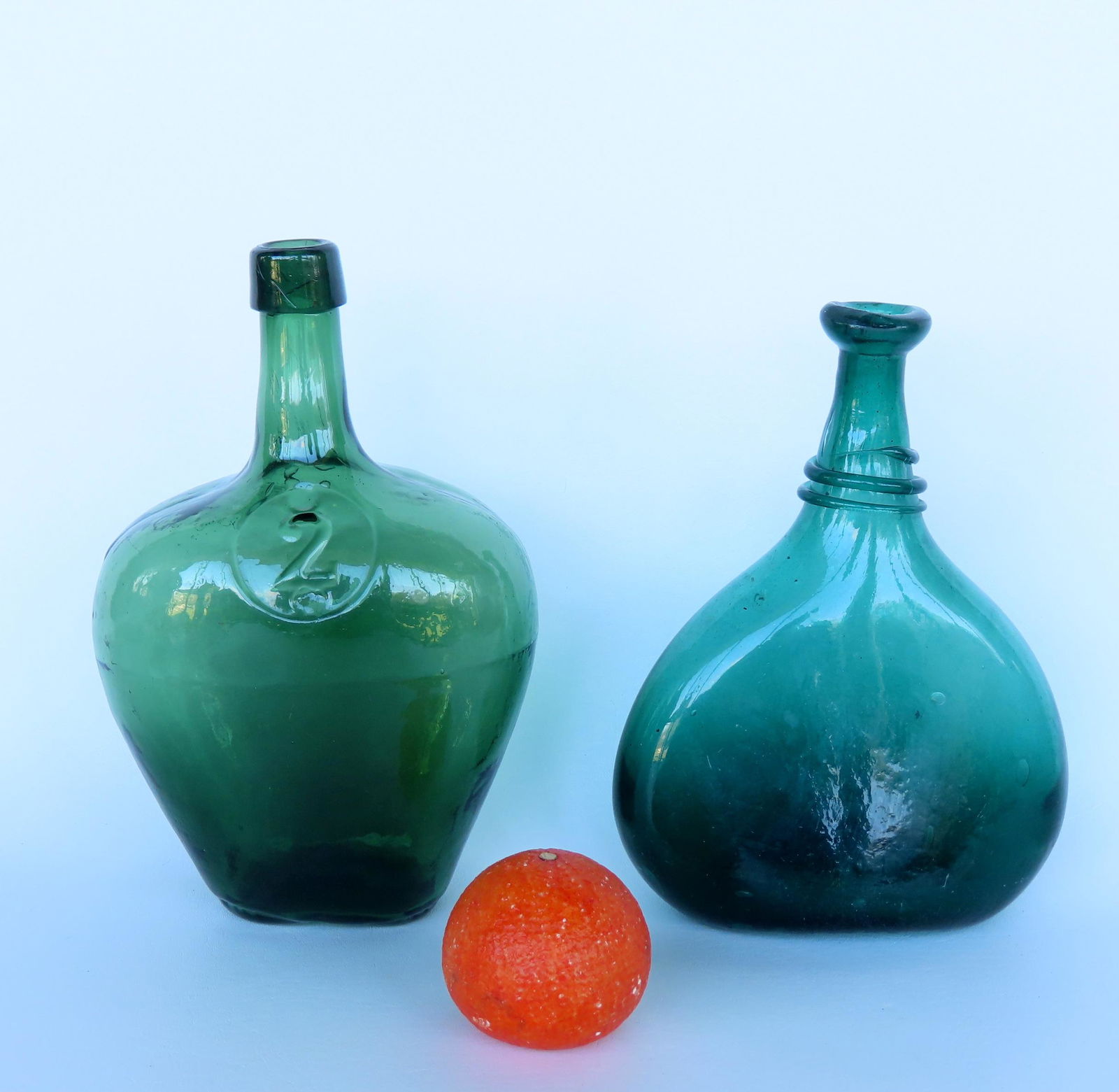 Two early bottles. The first a green Persian saddle flask with scarred ...