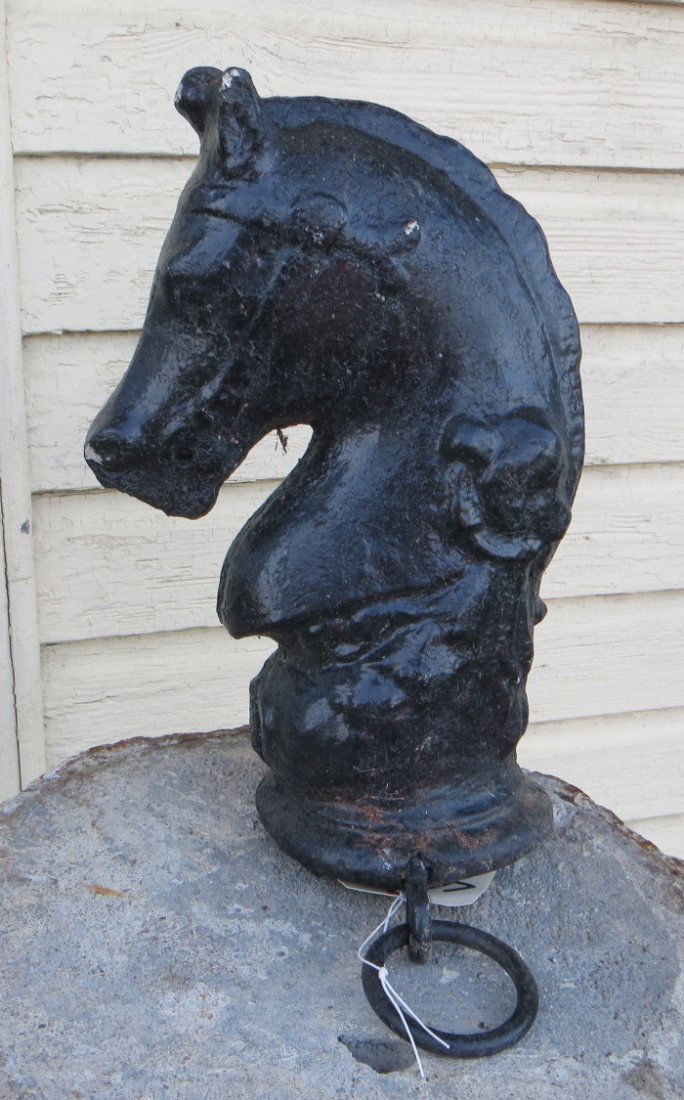 Concrete horse head hitching post in old black paint.
